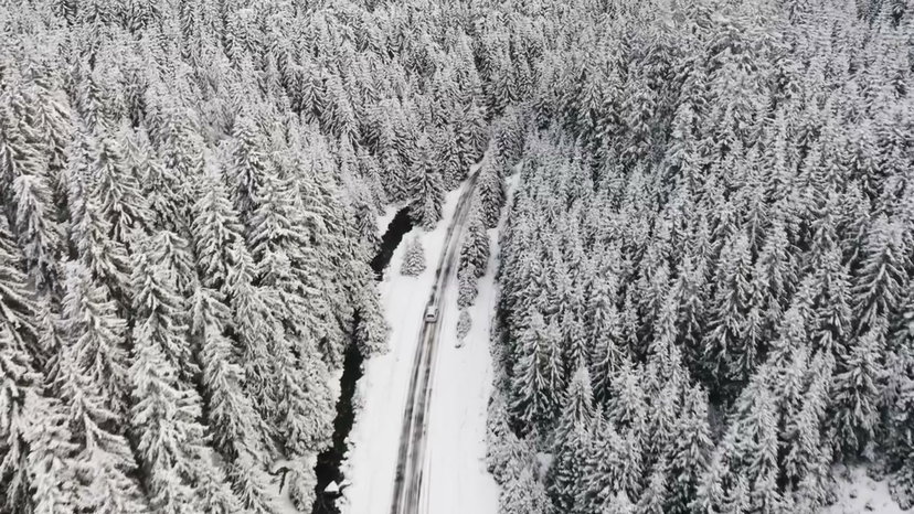 Aerial View of Car Driving Through Snowy Forest Road • Stock Video on ...