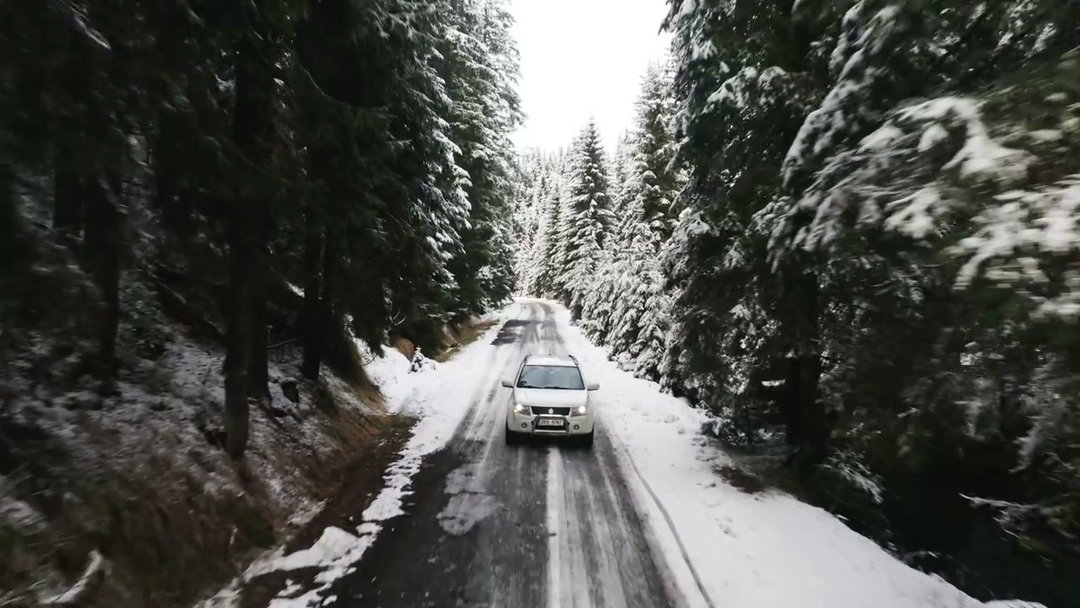 Aerial View of Car Driving Through Snowy Forest Road • Stock Video on ...