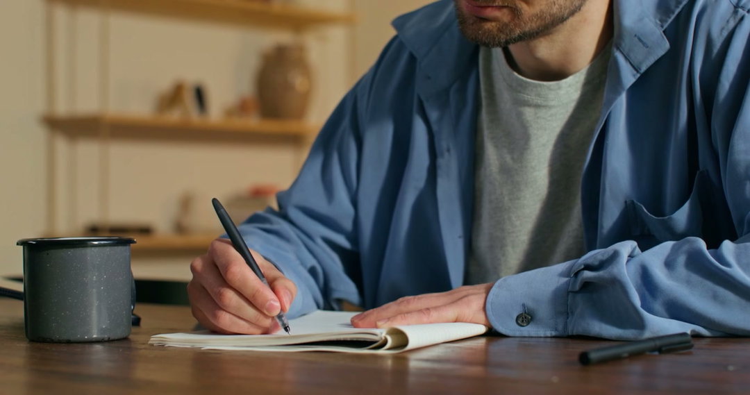 Focused Man Writing Notes in Home Office • Stock Video on Uppbeat